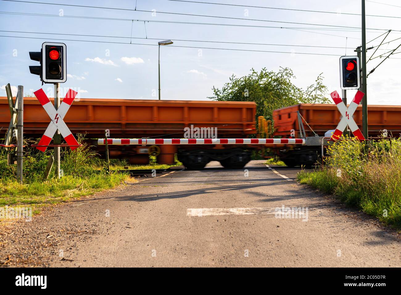 Closed barrier at the railroad crossing with red warning lights on ...