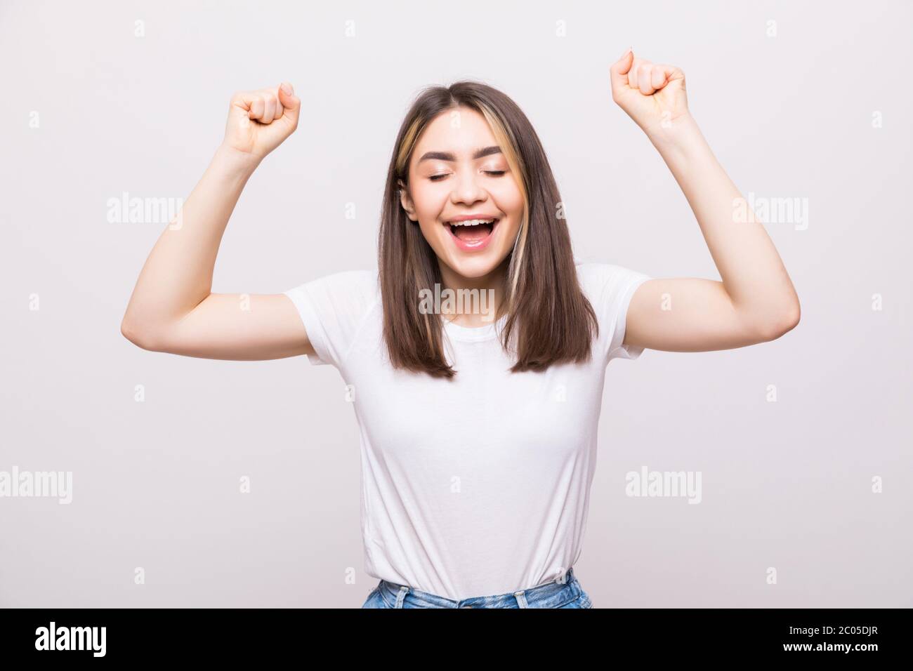 Portrait of a an excited young woman celebrating success over white ...