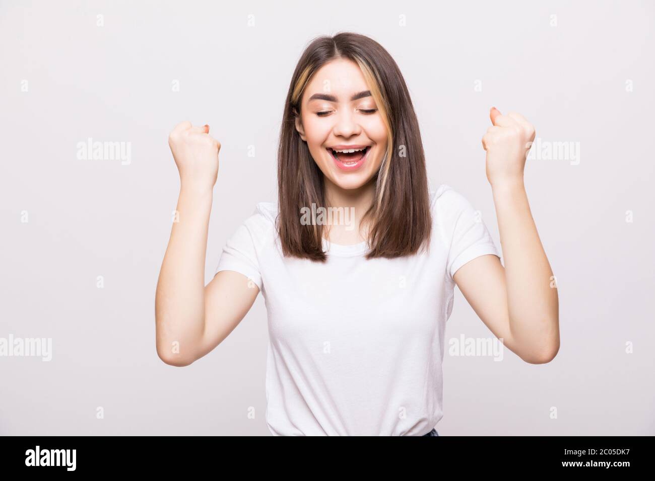 Portrait of a an excited young woman celebrating success over white ...