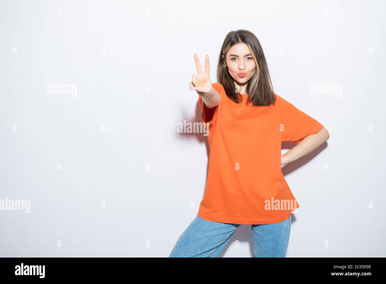 Cheerful smiling girl showing peace sign on white background Stock ...