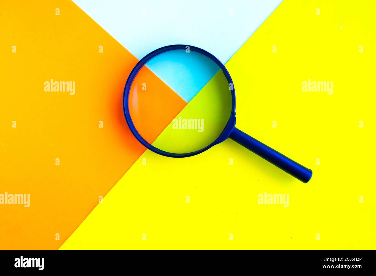 Magnifying glass on bright geometric orange and yellow background ...