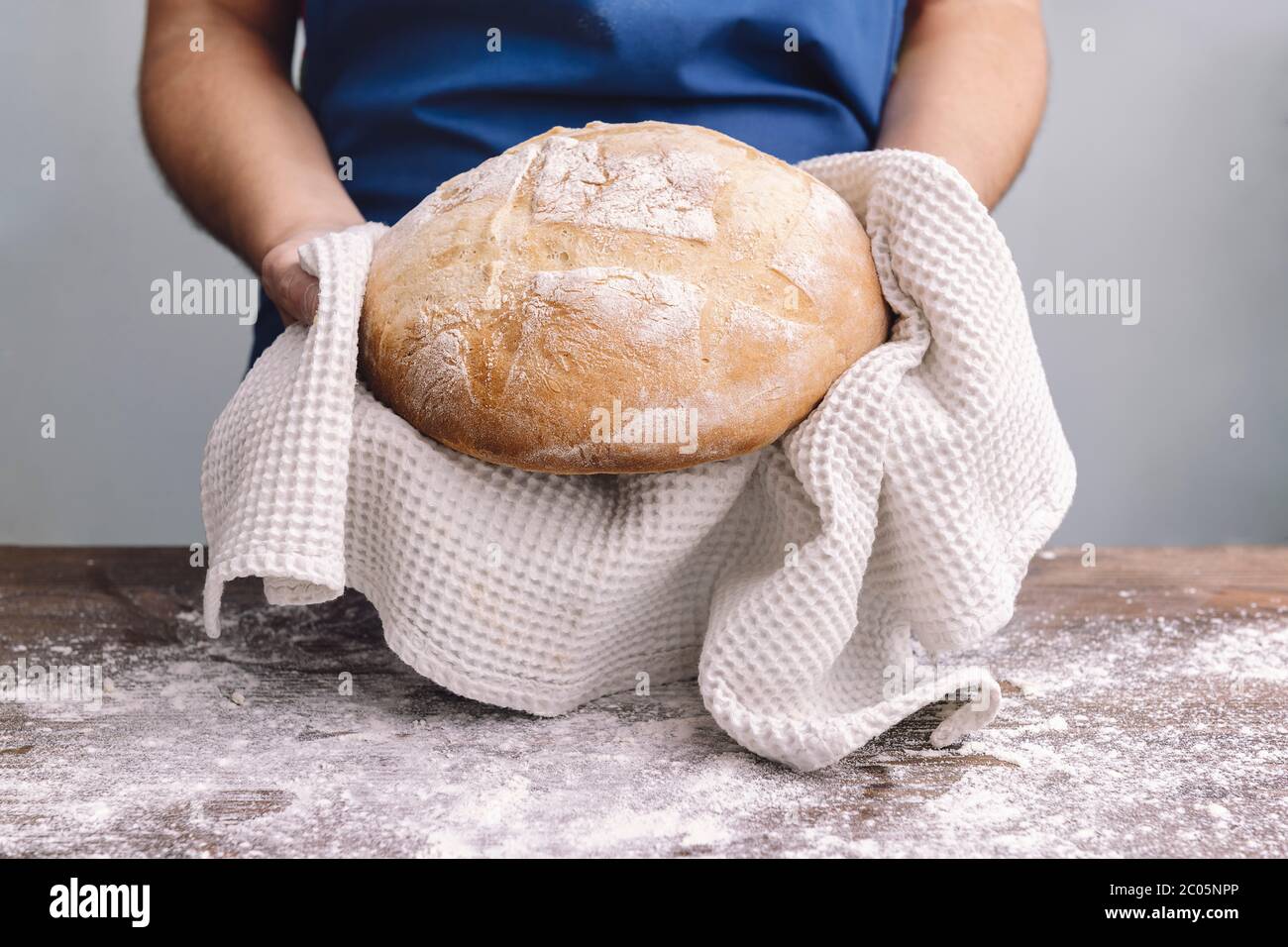 hands of an unrecognizable person holding a loaf of freshly baked bread ...