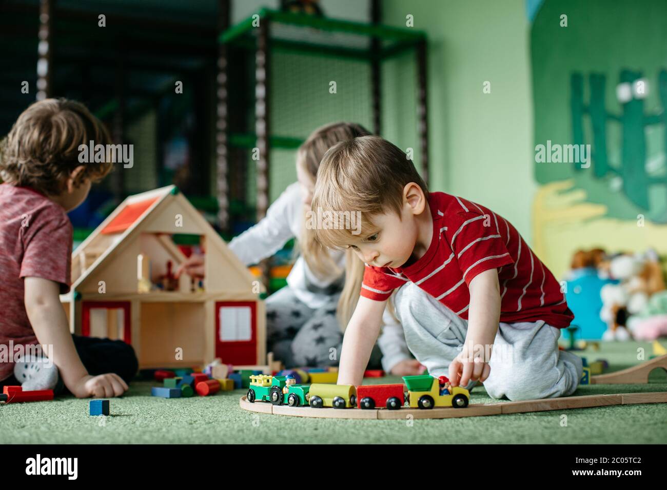 Little boy playing with a wooden train in an indoor playground Stock ...