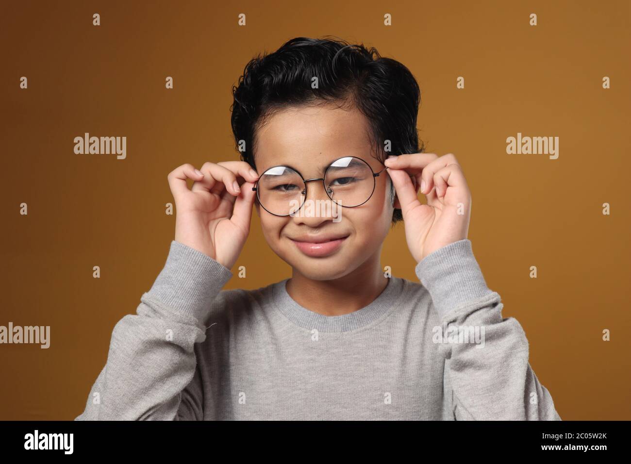 Portrait of Asian boy adjusting his eye glasses, sight problem concept ...