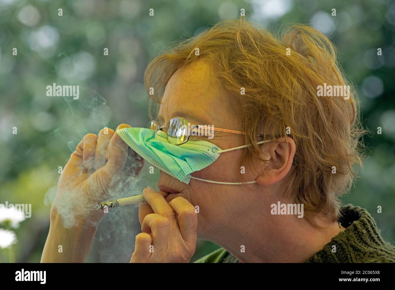 Older woman smoking with a face mask, portrait, cigarette break, corona ...