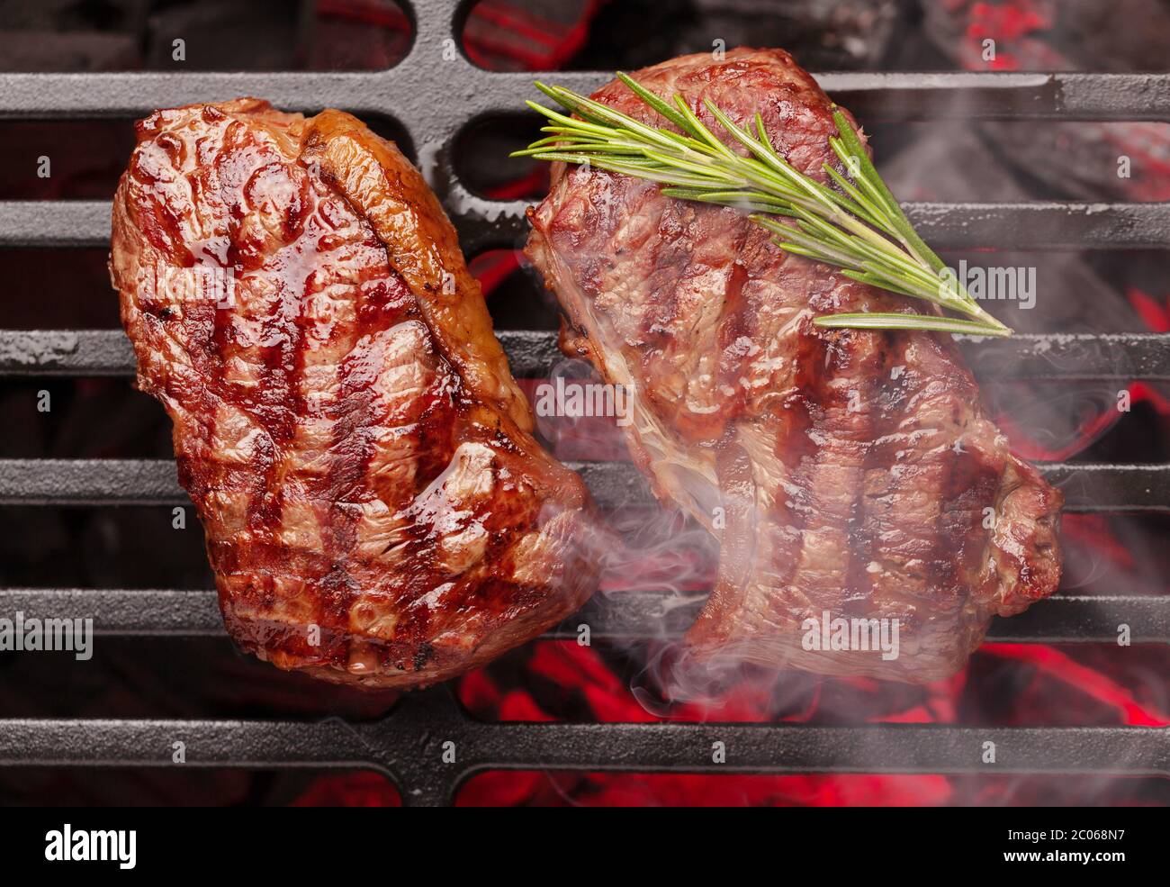 Beef steaks cooking on grill with spices and herbs. Top view flat lay ...