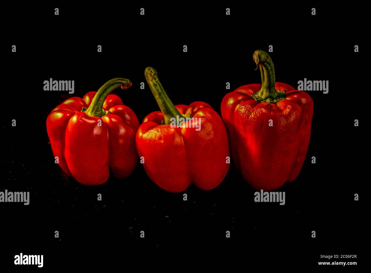 three beautiful ripe red bell peppers on a black studio background ...