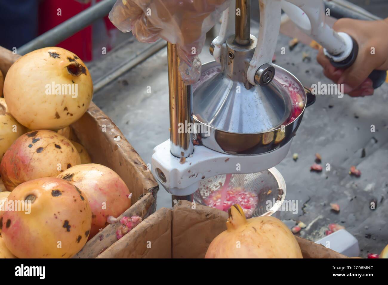 Hand squeezing a fresh pomegranate juice on a street food market in ...