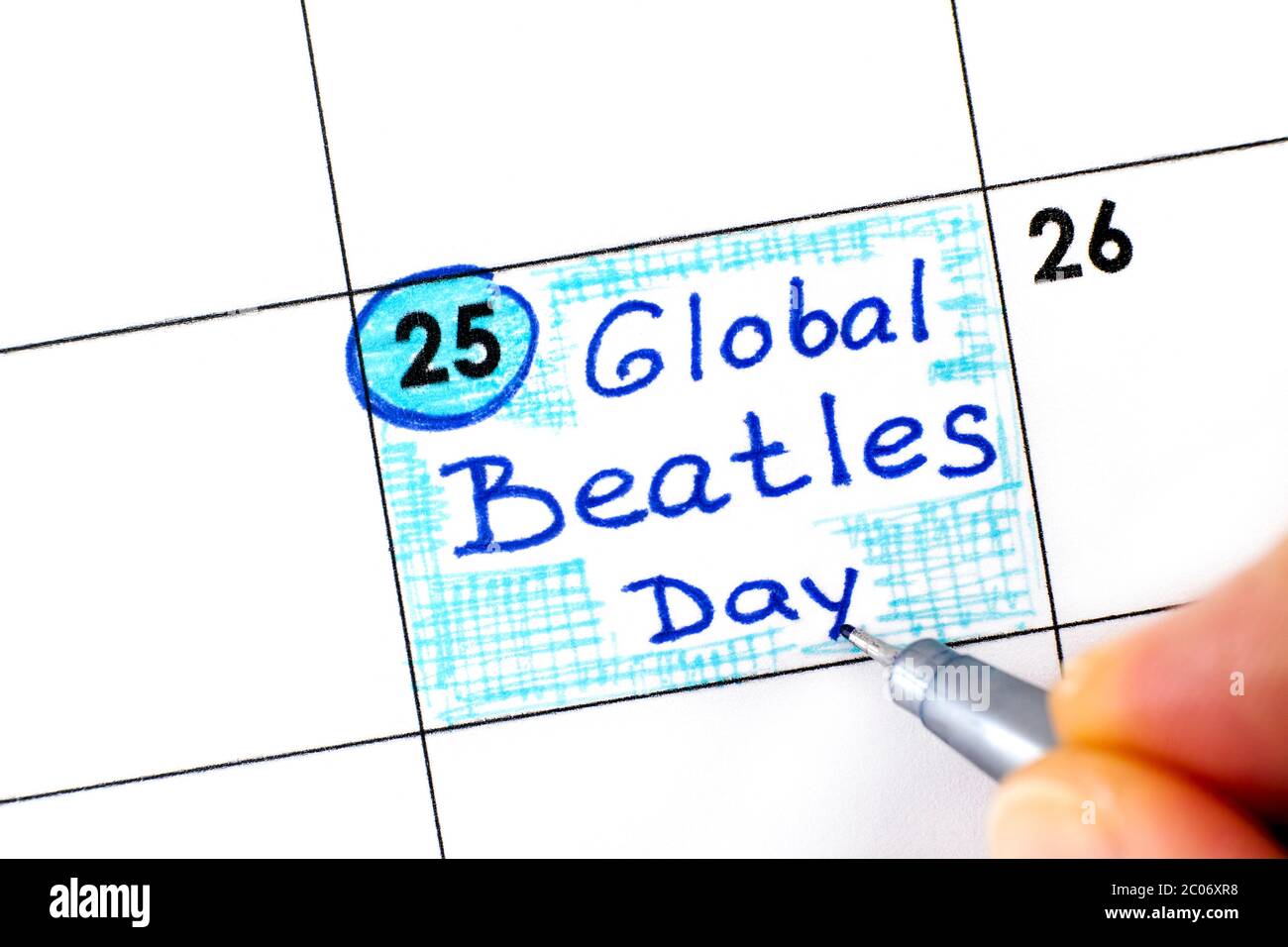Woman fingers with pen writing reminder Global Beatles Day in calendar ...
