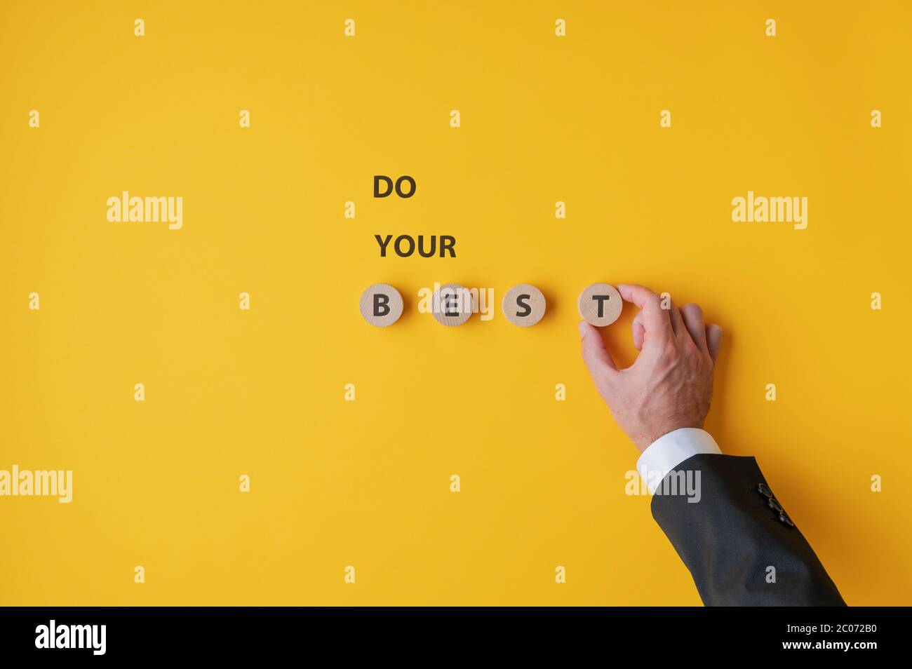 Hand of a businessman making a Do your best sign spelled on yellow ...