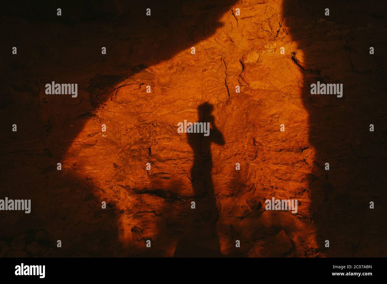 silhouette of person against red cave entrance at sunset in desert ...