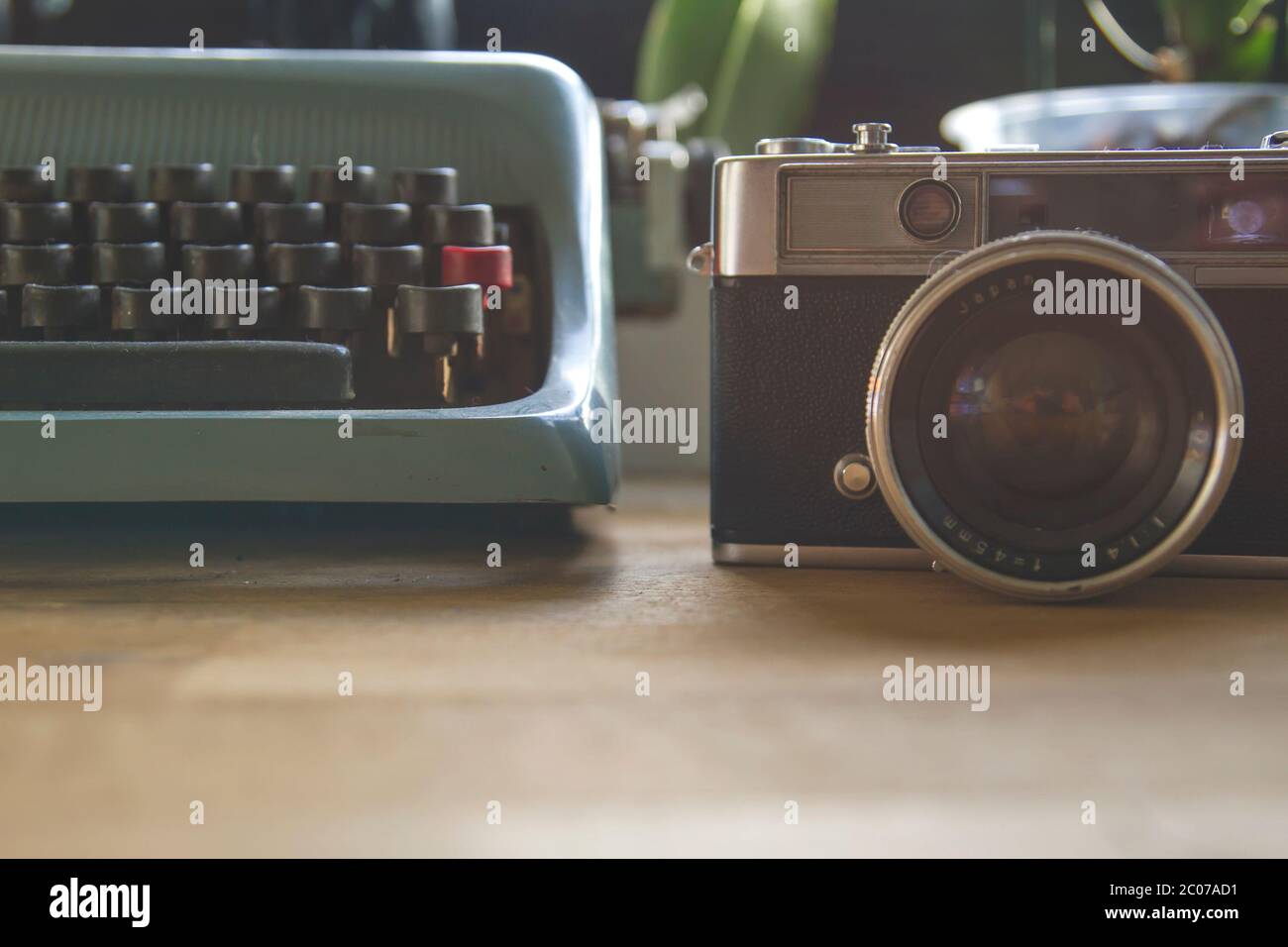 Old photo camera and blue vintage typewriter on a desk Stock Photo - Alamy