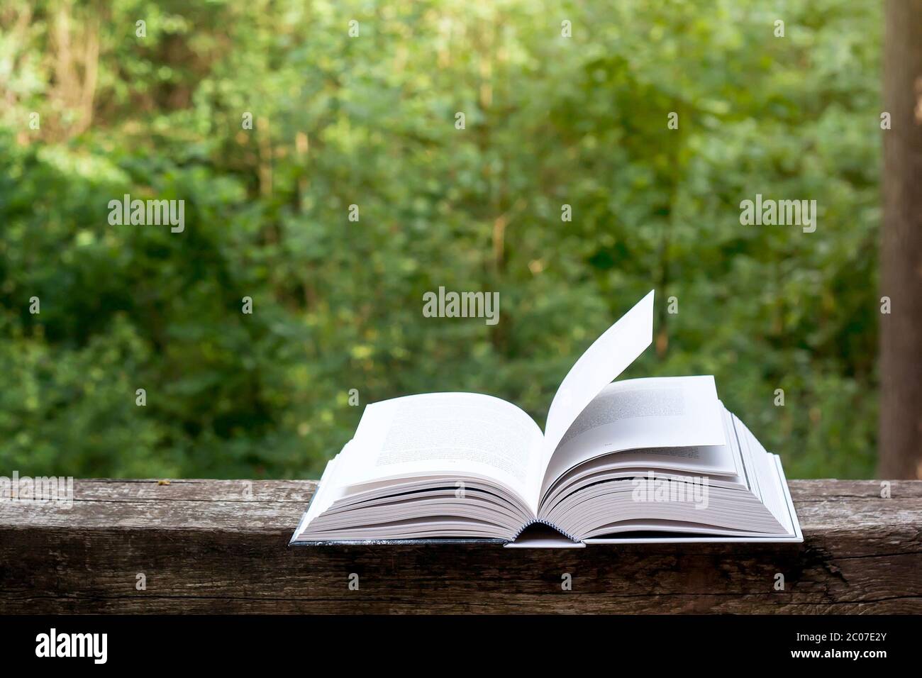 Open book on the garden wooden table Stock Photo - Alamy