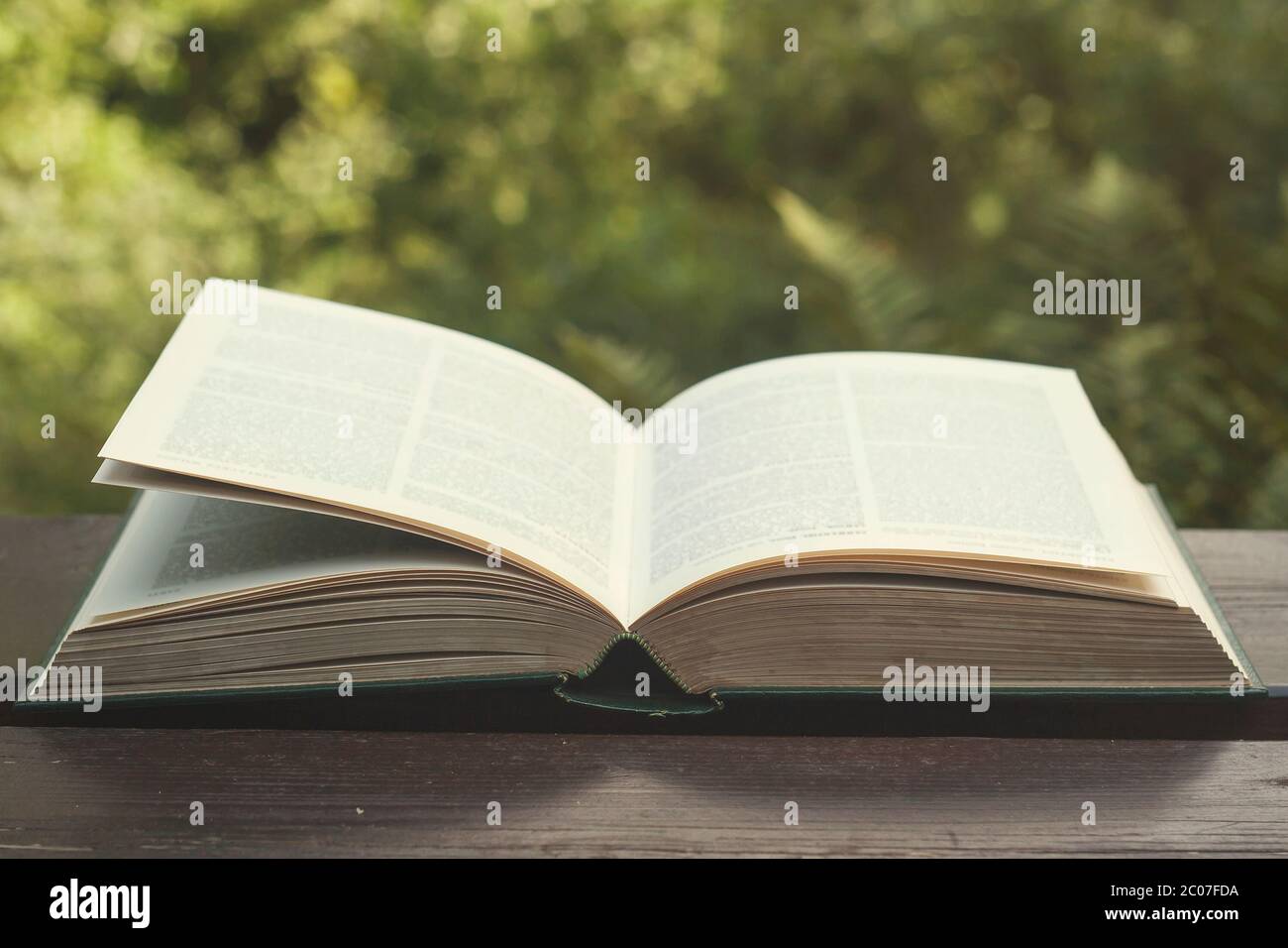 Open book on the garden wooden table Stock Photo - Alamy