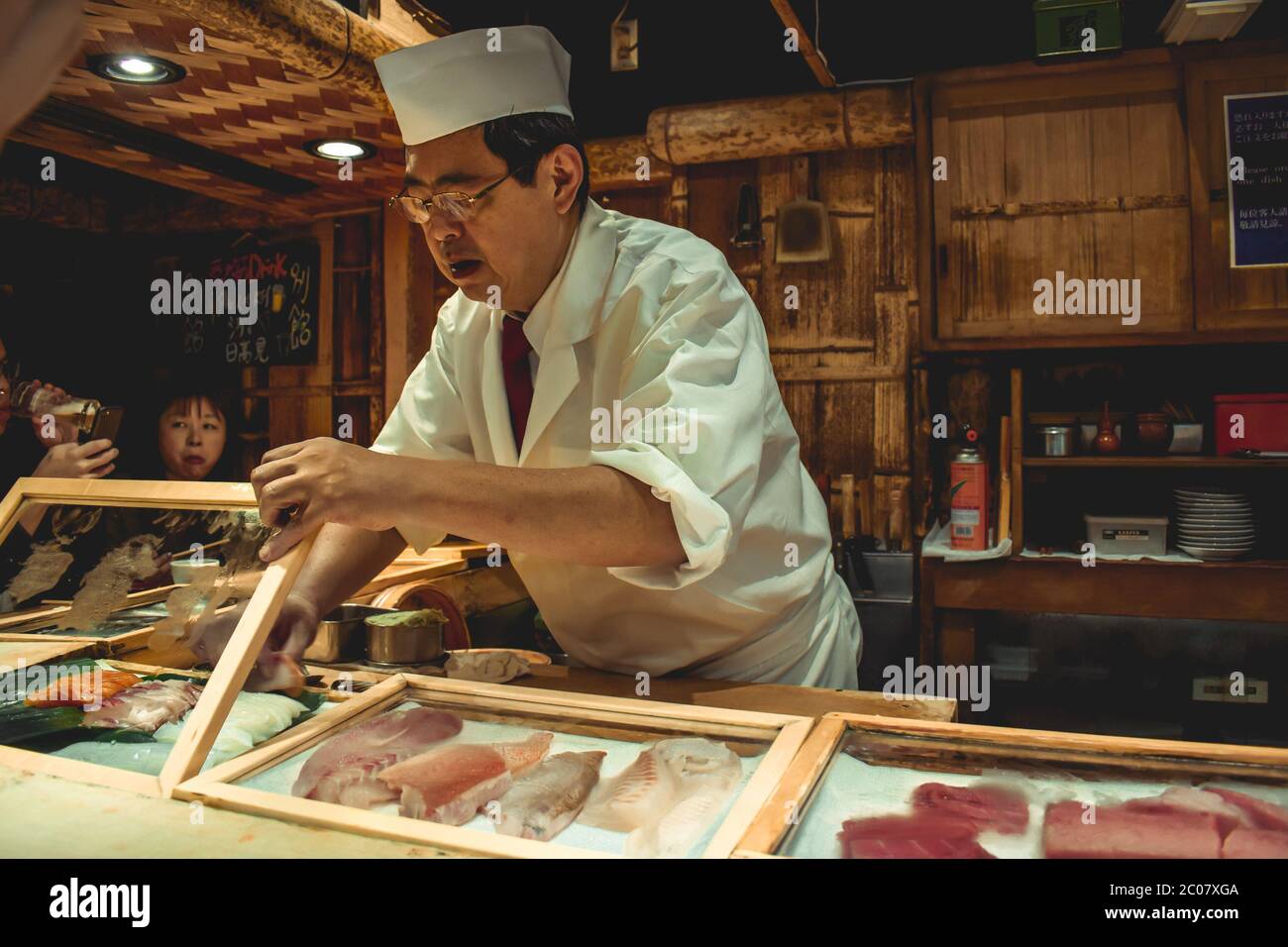 Sushi master chef preparing fresh sashimi for hungry customers in a ...