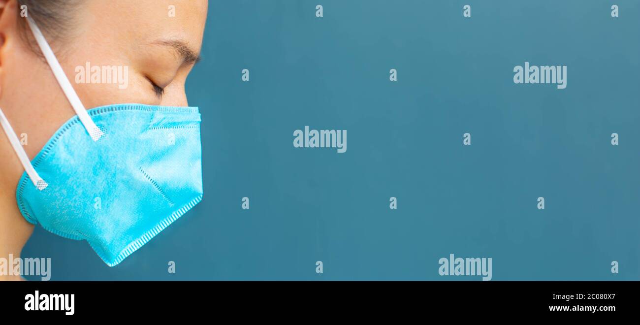 Girl wearing a surgical mask and her eyes closed against a aqua bleu ...