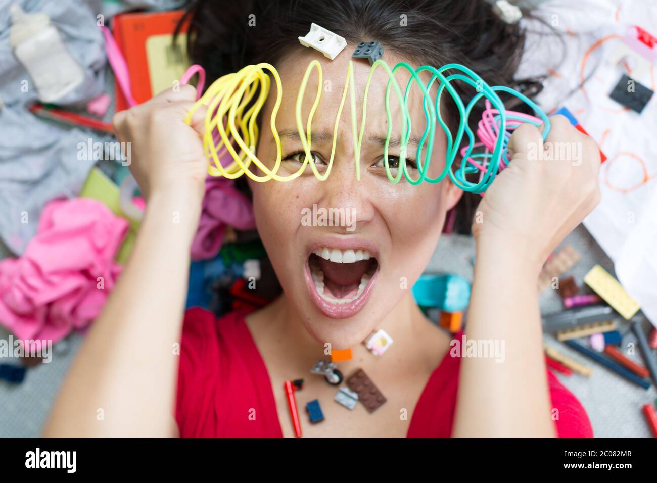 A mom lying in a pile of mess and toys at home, busy life at home Stock ...