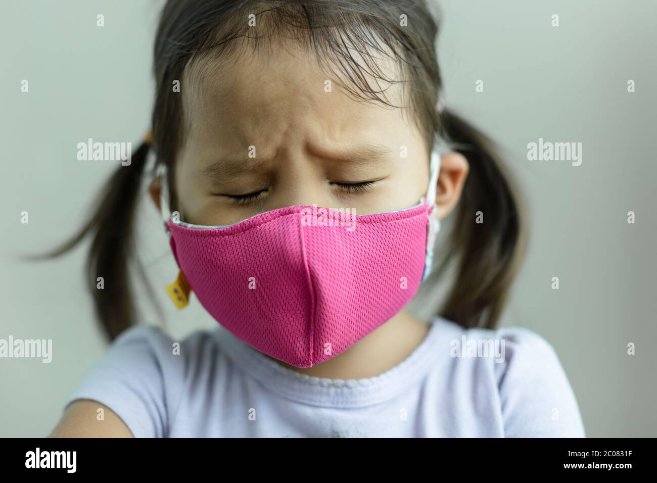 A sad stressed child looking down coughing from a bad sickness, wearing ...