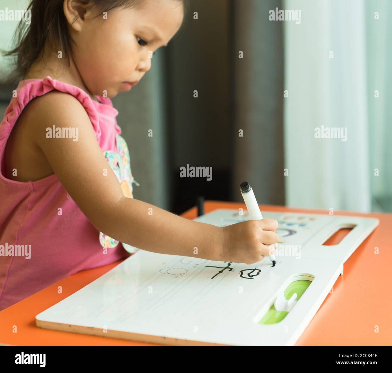 A young child practing her writing hand coordination skills with a book ...