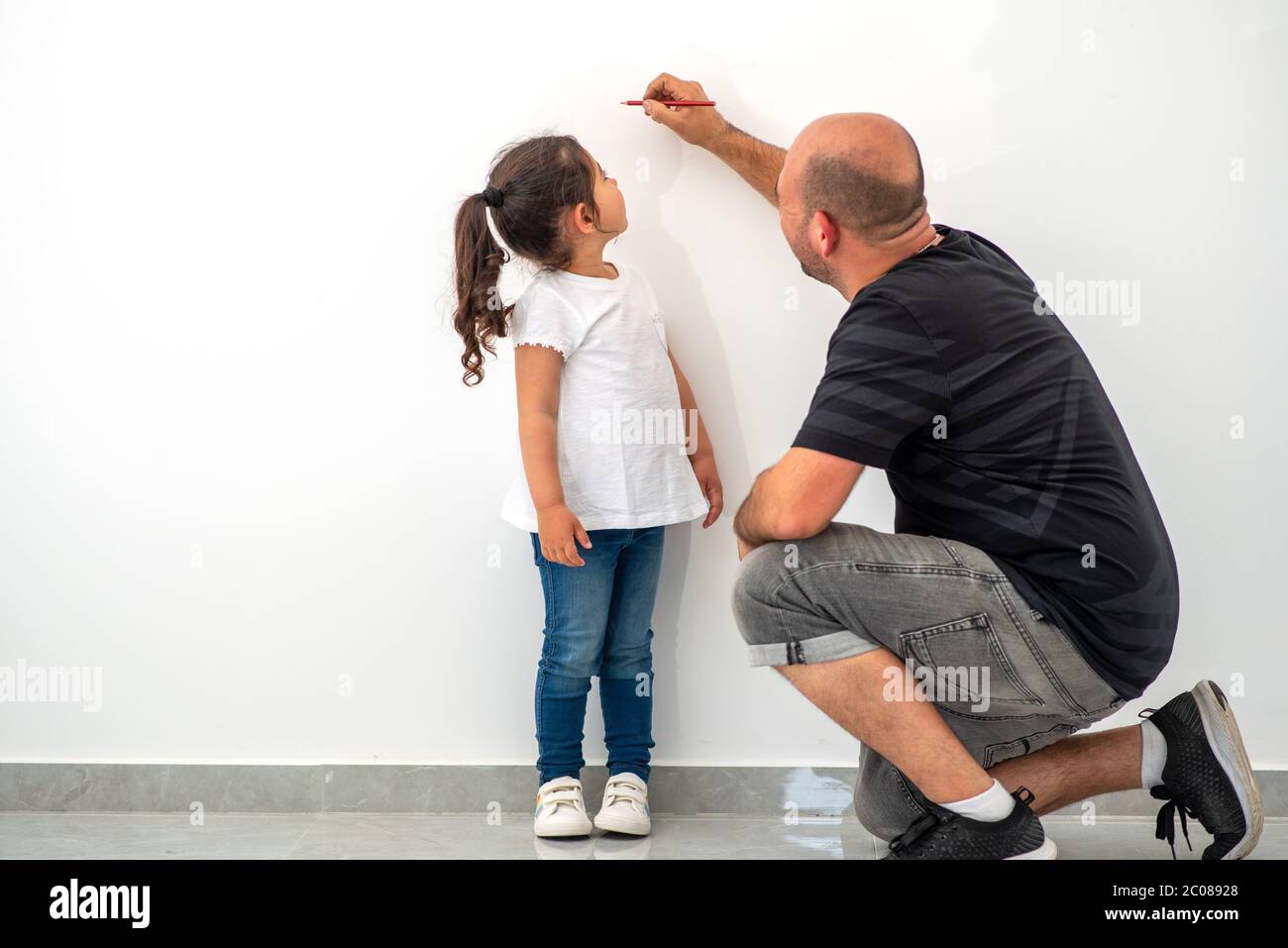Father measuring height of a cute child. Dad measures the growth of her ...