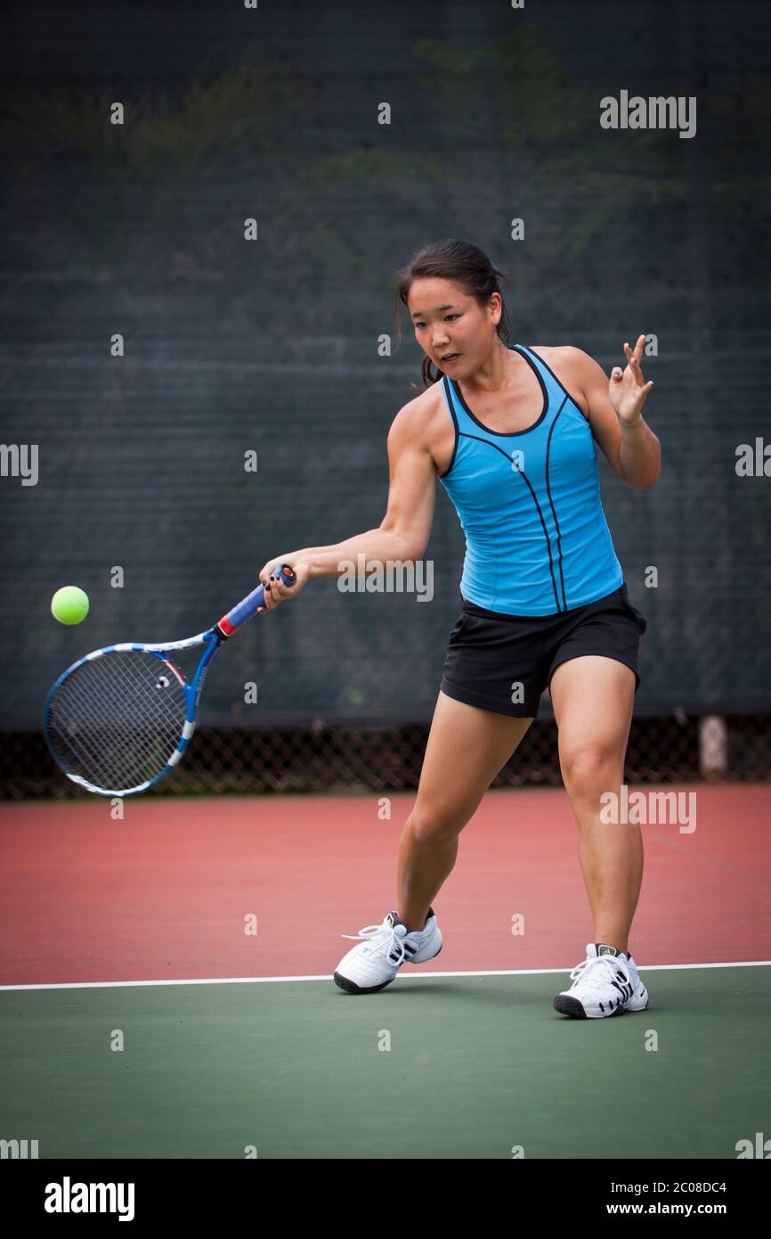 Young Japanese tennis player (model released) prepares to hit forehand ...