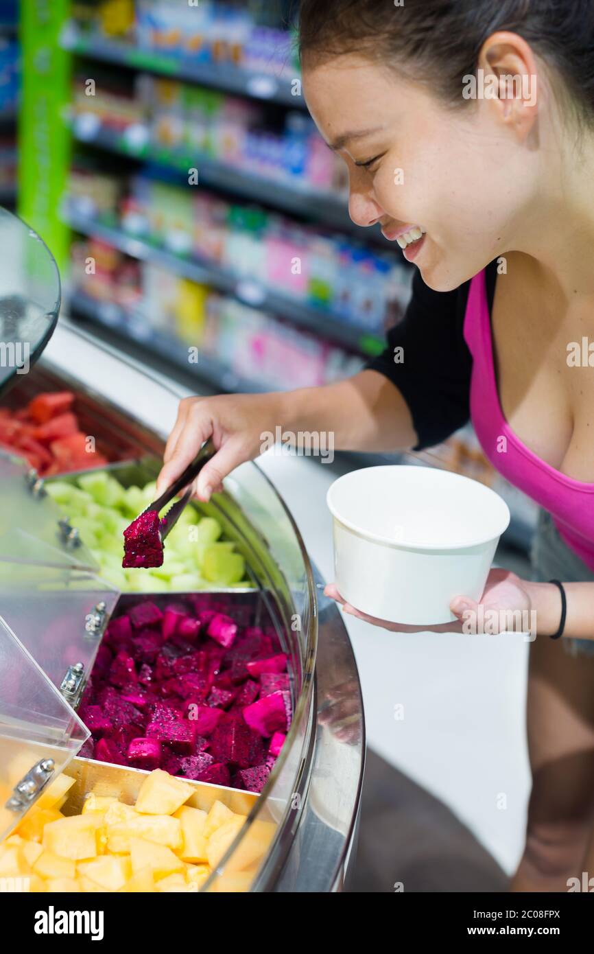 A customer choosing a healthy selection of fruit at the grocery buffet ...