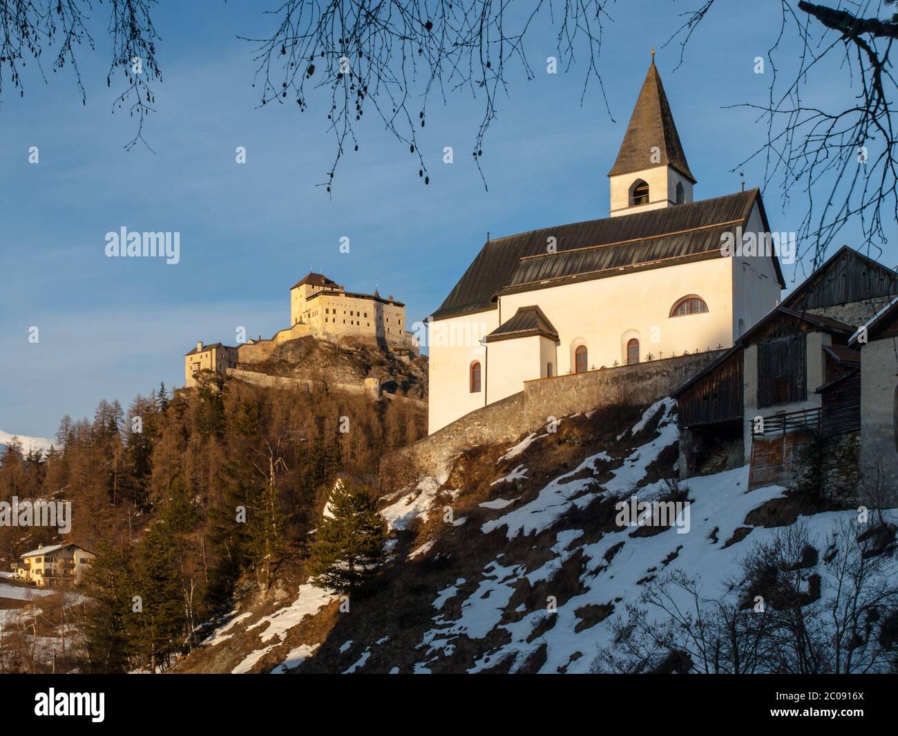 Small rural church and castle on the background in Tarasp village ...