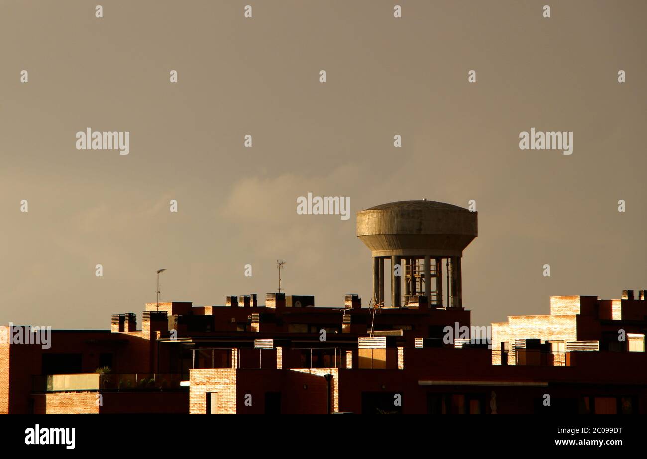 Sun reflecting on red brick buildings and a water tower wet after a ...