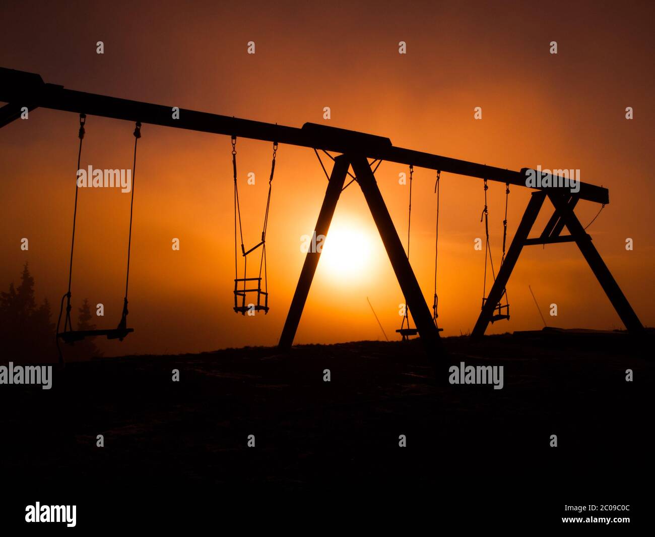 Empty swings on children playground at sunset time Stock Photo - Alamy