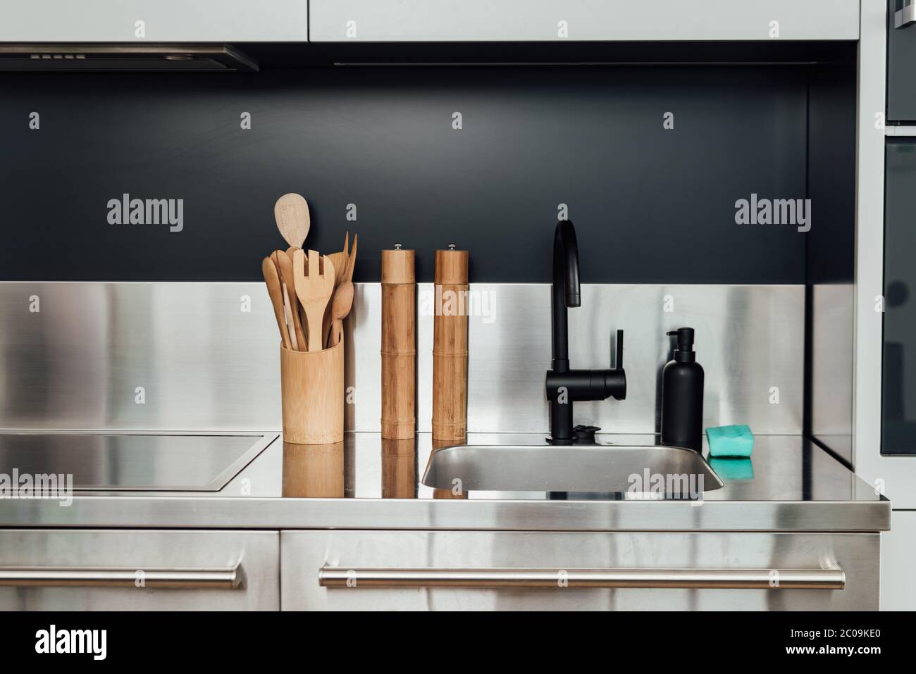 wooden pepper mill and salt mill near faucet, sink, soap dispenser and ...