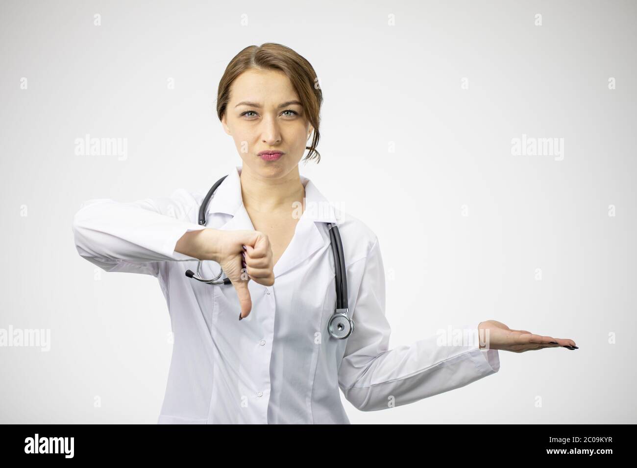 Beautiful displeased doctor in medical uniform shows dislike holding ...