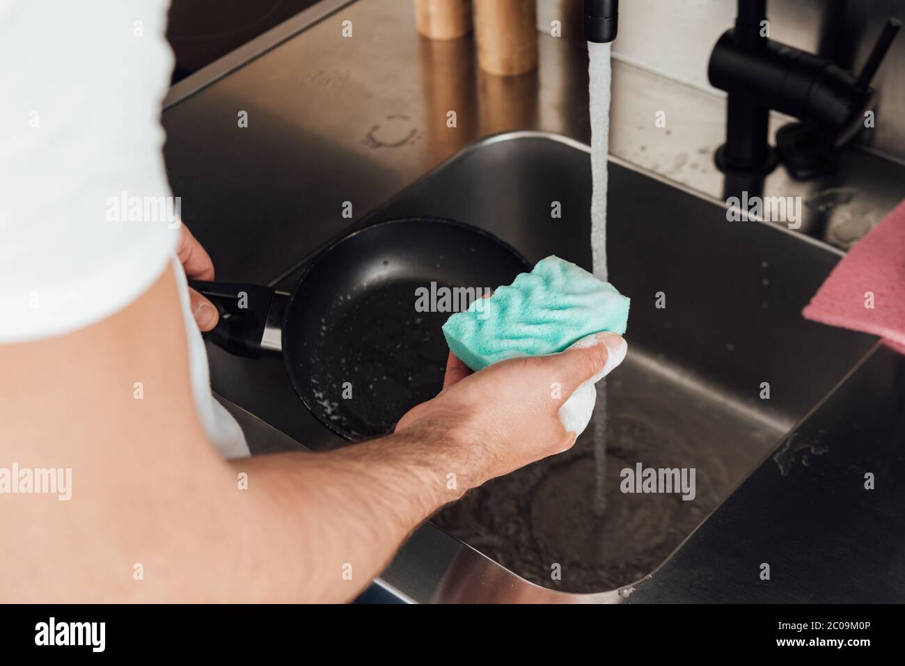 Cropped view of man cleaning frying pan with sponge in kitchen Stock ...