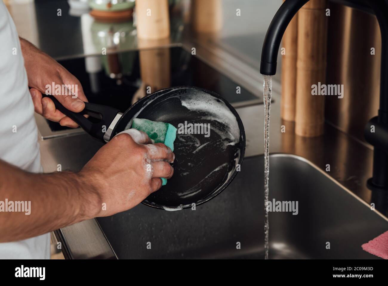 Cropped view of man cleaning frying pan in kitchen Stock Photo - Alamy