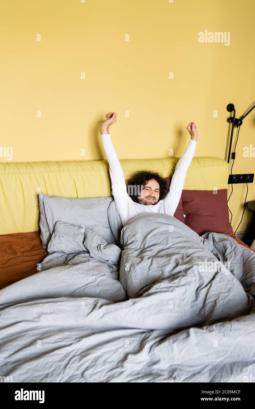 Smiling man stretching while lying in bed Stock Photo - Alamy