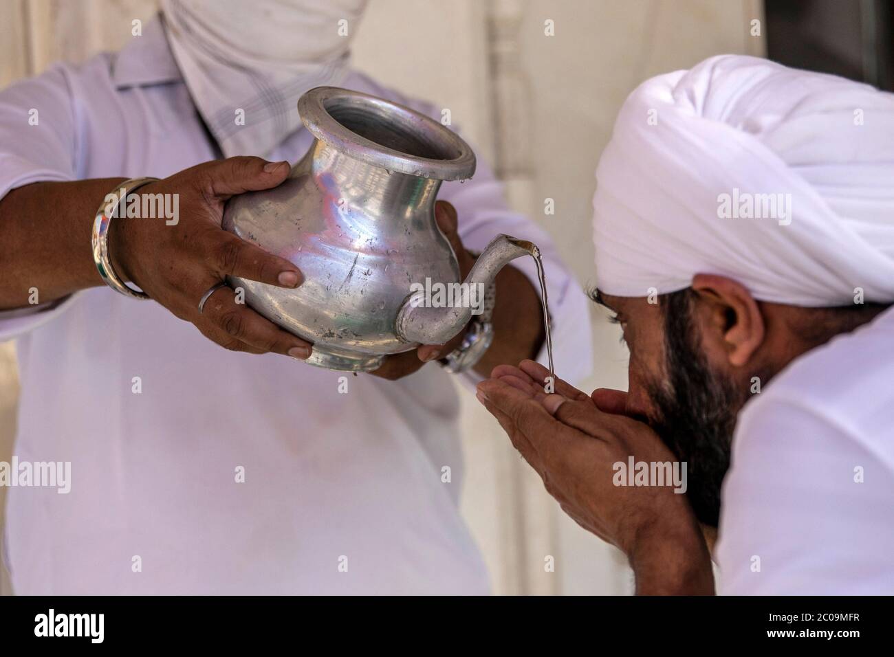 A sikh volunteer offering Holy water inside Bangla Sahib Gurudwara ...