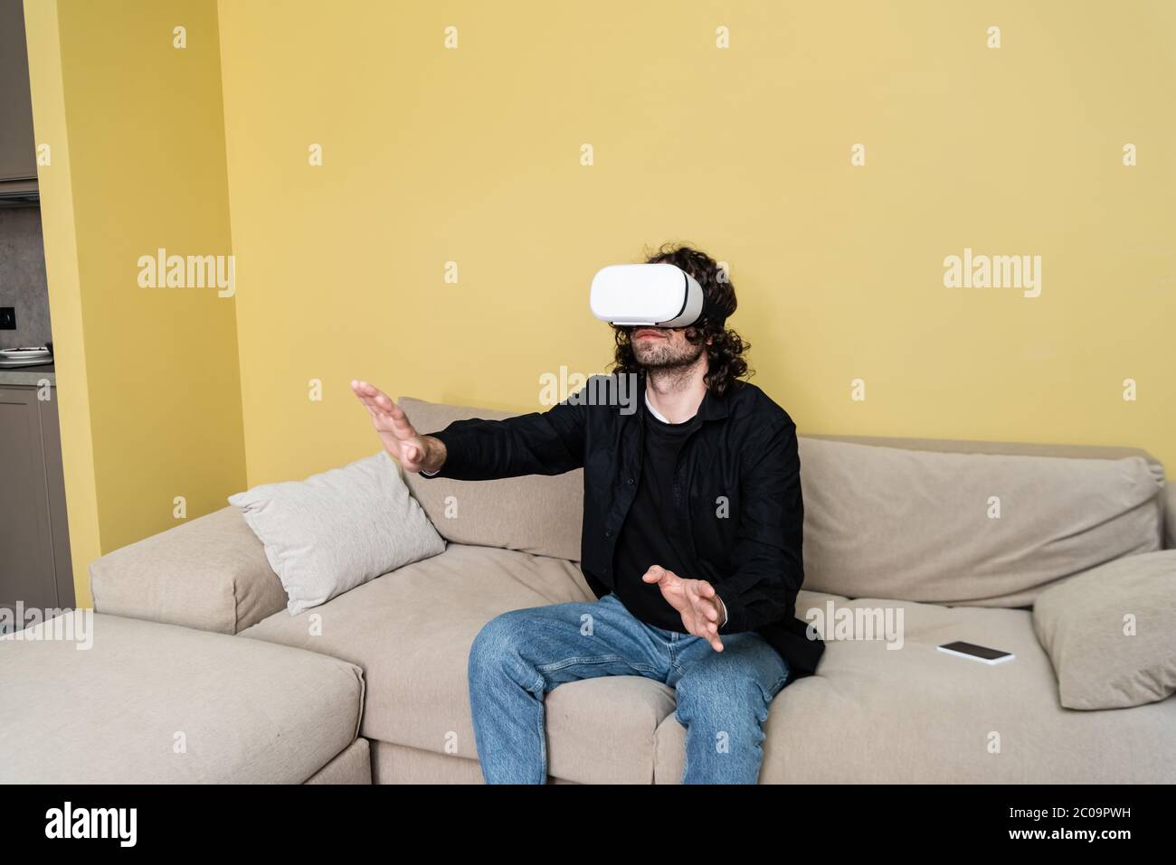 Man in virtual reality headset playing video game on sofa at home Stock ...