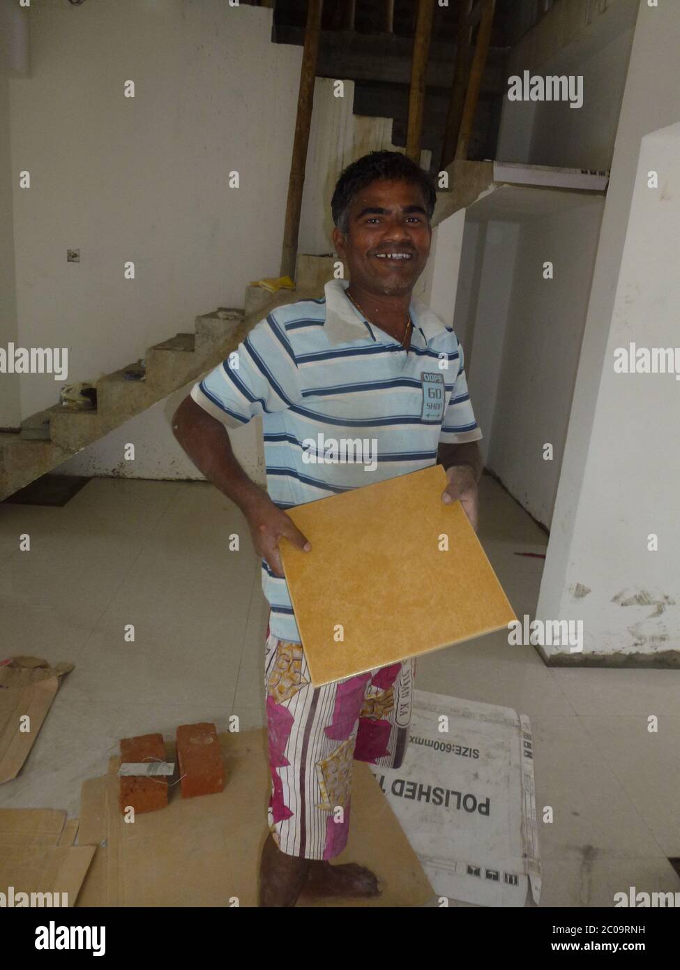The head Mason smiling happily with a floor tile in hand Stock Photo ...