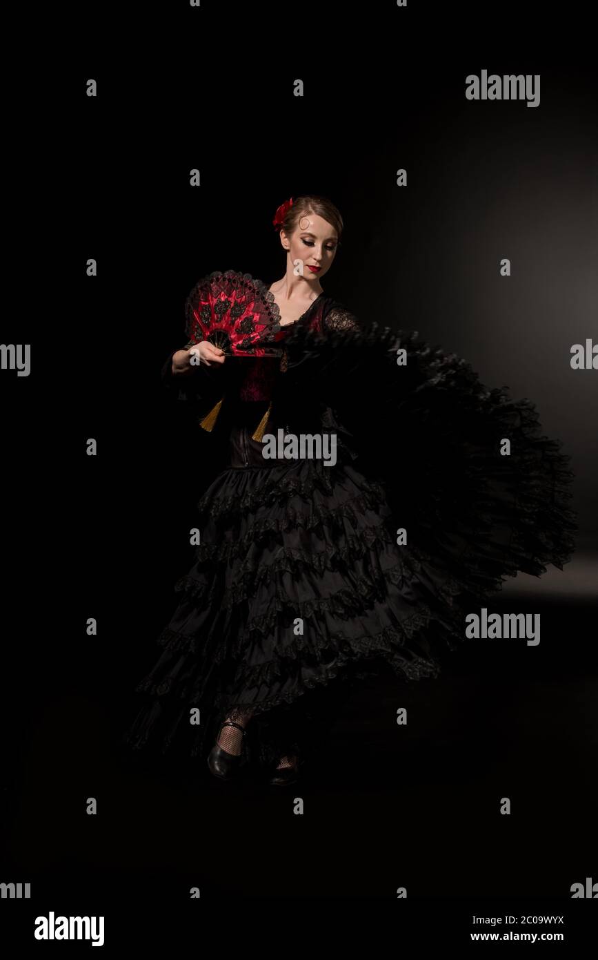 young flamenco dancer holding fan and dancing on black Stock Photo - Alamy