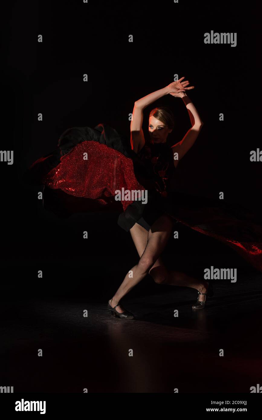 pretty young dancer with hands above head dancing flamenco on black ...