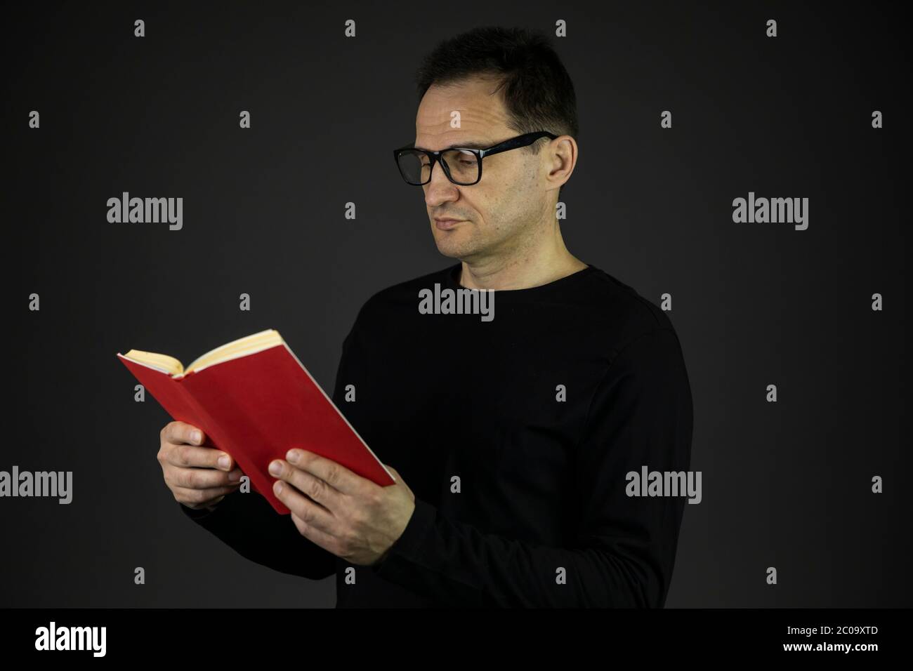 Smart man in casual black wear and glasses relaxing reading interesting ...