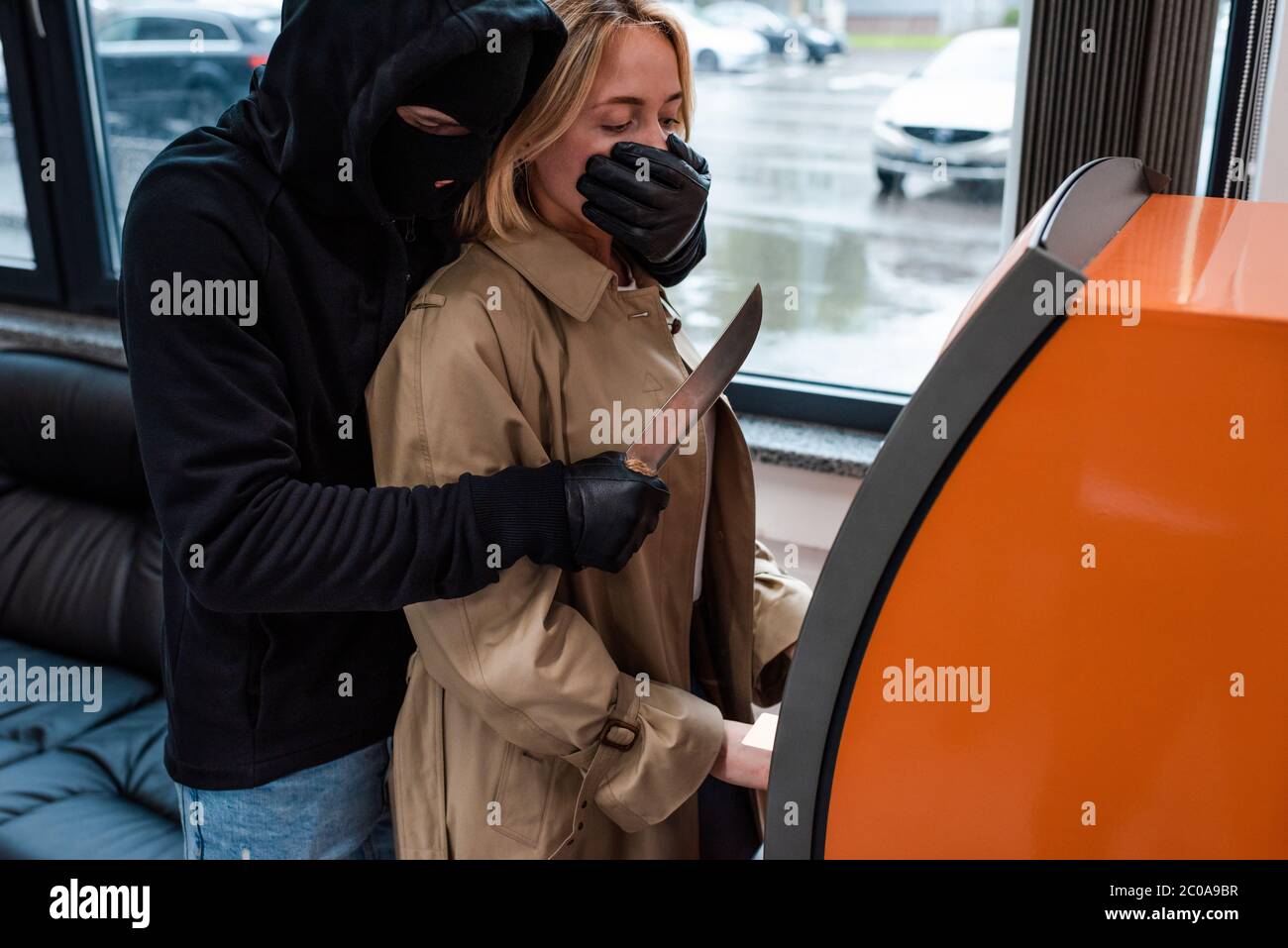 Robber in mask holding knife near woman using atm Stock Photo - Alamy