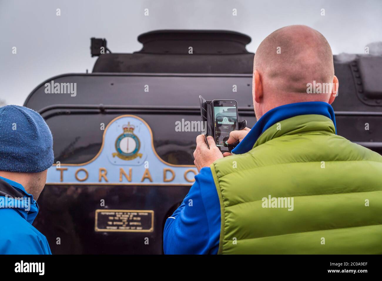 Rear view of male rail enthusiast taking photo on mobile phone of UK ...