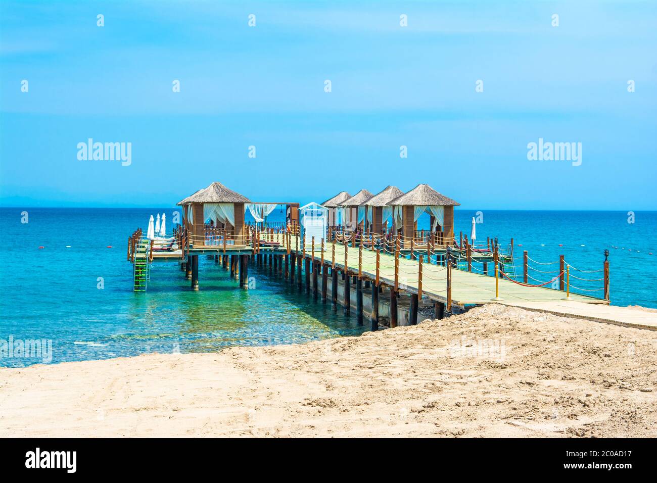 Wooden beach pavilions on the shore of a sandy beach - the ...