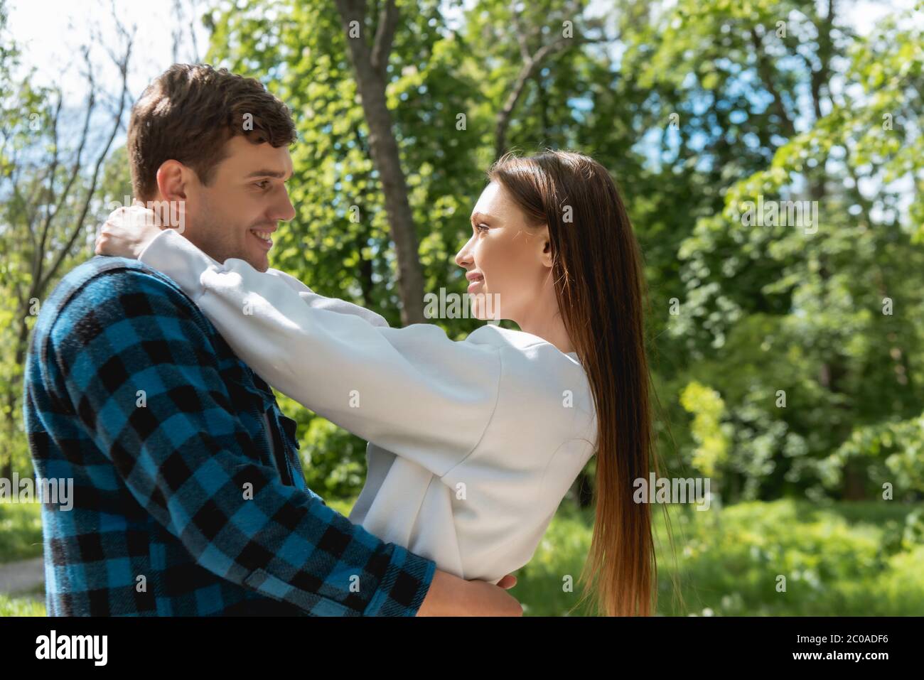 side view of happy and young couple hugging in park Stock Photo - Alamy