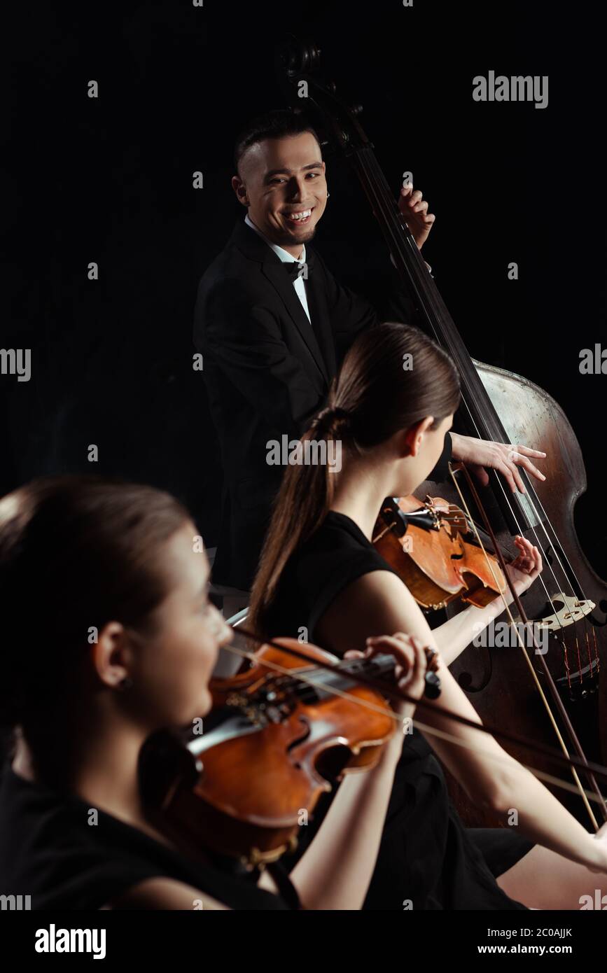 happy professional musicians playing on double bass and violins ...