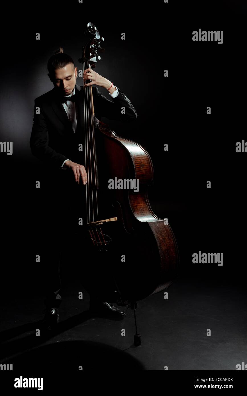 professional male musician playing on contrabass on dark stage Stock ...