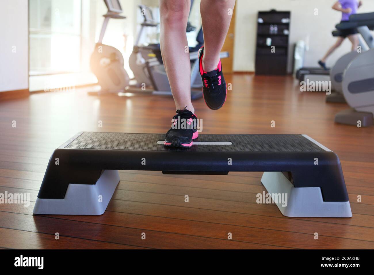 Woman doing step aerobics while in health club Stock Photo - Alamy
