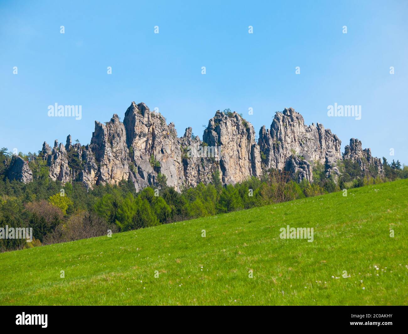 Sharp sand stone rock formation with green meadow and blue sky Stock ...
