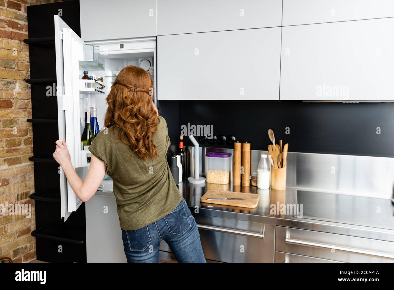 Back view of woman standing near open fridge in kitchen Stock Photo - Alamy
