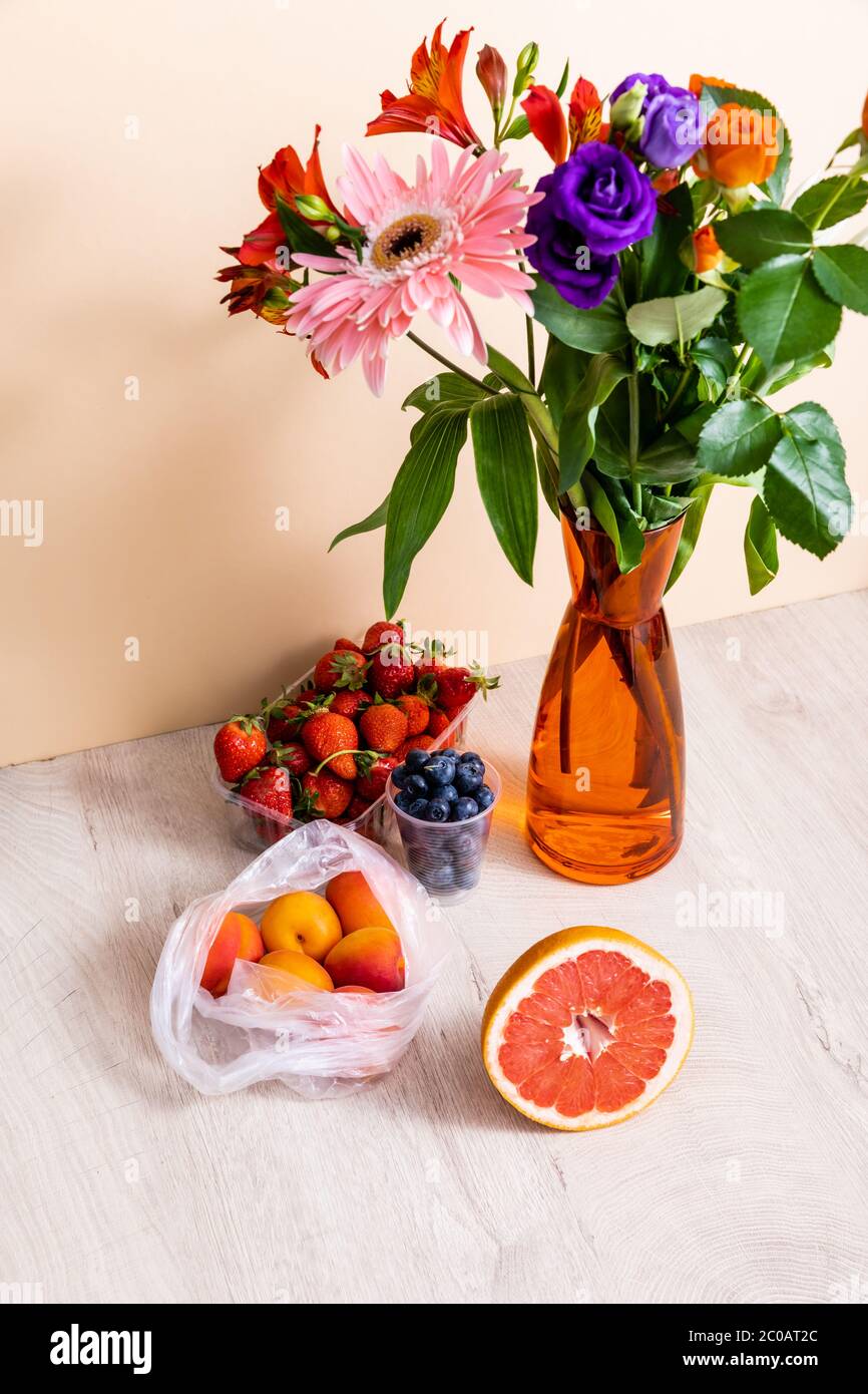 floral and fruit composition with bouquet in vase, berries, grapefruit ...